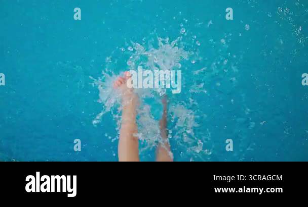 Happy splashing feet in blue swimming pool water representing joyful ...