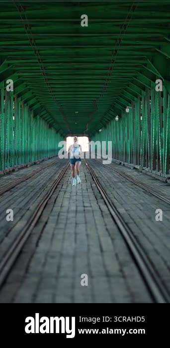 Morning jog, lens blur, pretty woman running through a bridge over the ...