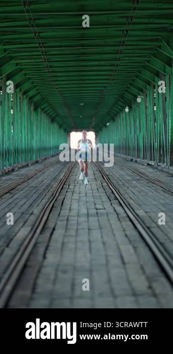 Morning jog, pretty woman running on a bridge over a river, cardio ...