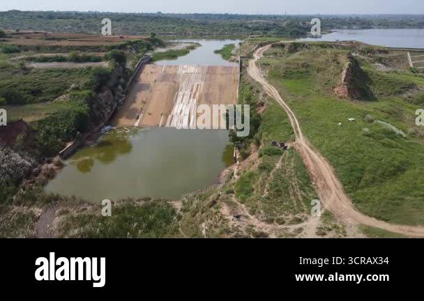 Panoramic view of small dam spillway releasing water flow showing rural ...