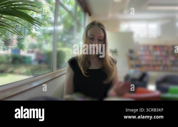 A young woman looking through a brochure in a library. High quality 4k ...
