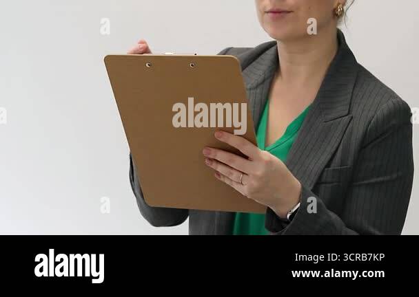 Close up of a woman holding a clipboard and writing with a pen and ...