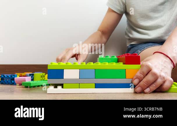 Woman sitting on floor playing with colorful plastic construction ...