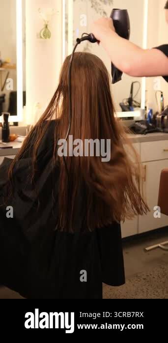 Beauty salon scene with stylist blow drying long straight hair of ...