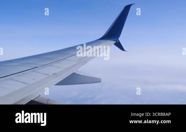 View from an airplane window showing the wing flying high above fluffy ...