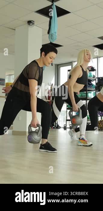 A group of people exercise with dumbbells in a bright modern gym. The ...