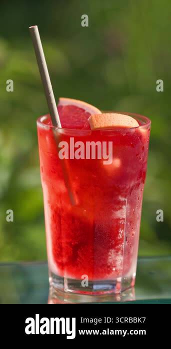 glass of classic red spritz cocktail with ice and straw and grapefruit ...