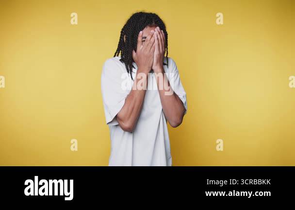 footage of young man with dreadlocks is covering their face in a ...