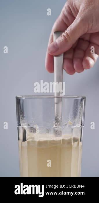 human hand mixing protein powder with water in glass. whey sports ...