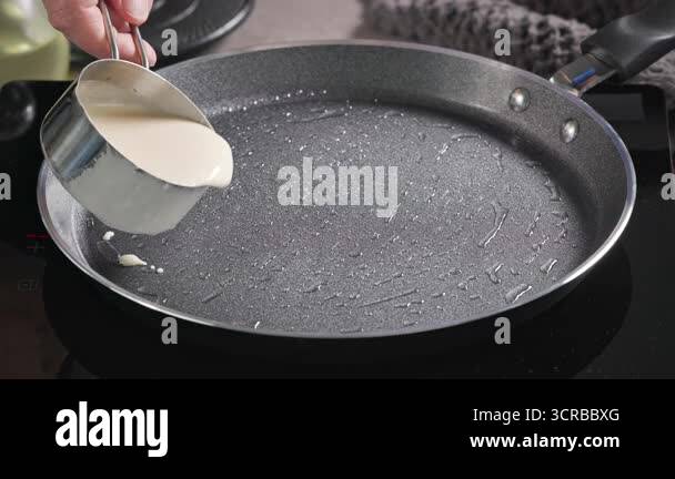 pancake batter pouring in hot frying pan on stovetop using measure ...