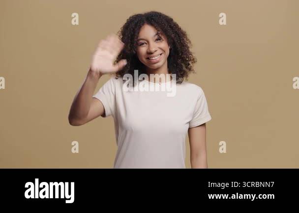 Friendly young african american woman waving hand - hello, or salute ...