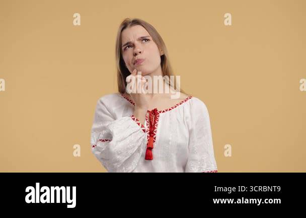 Thinking around ukrainian woman on beige studio background. Smart lady ...