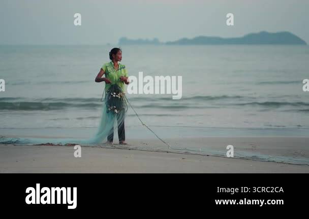 Fisherwoman tying a fishing net after a fishing day on Ao Thung Makham ...
