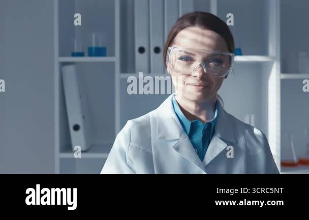 A determined female scientist in a lab coat and safety goggles ...