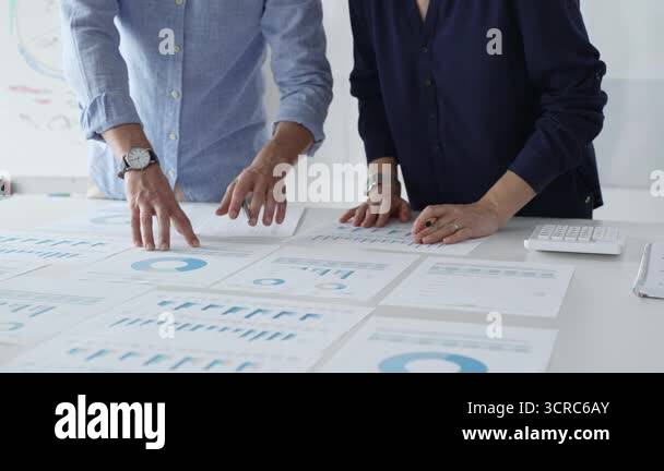 Business colleagues are examining financial reports and pointing at ...