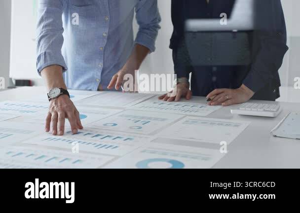 Business colleagues are examining financial reports and pointing at ...