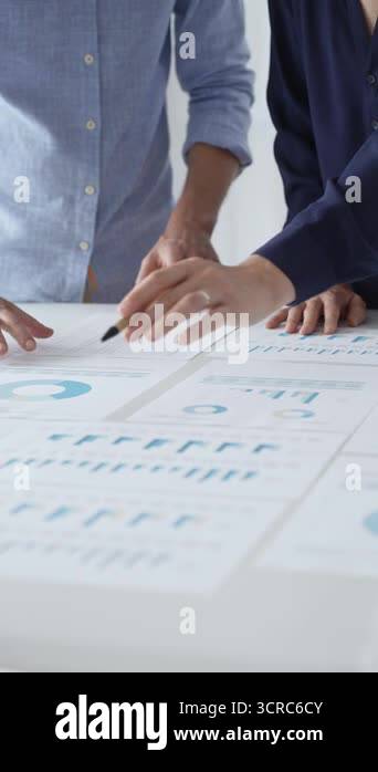 Business colleagues are examining financial reports and pointing at ...