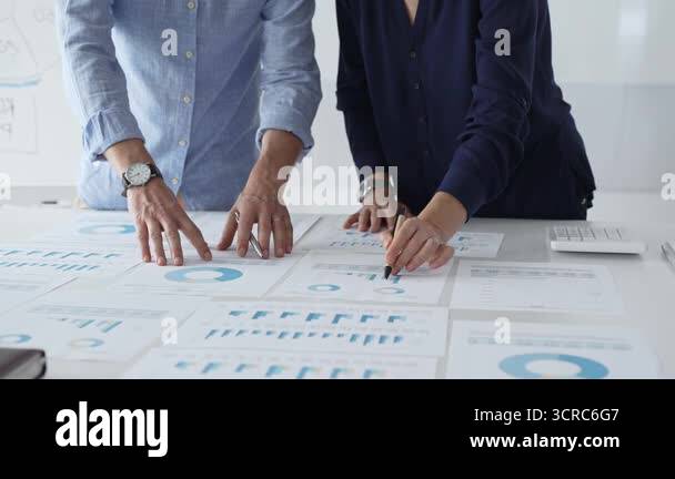 Business colleagues are examining financial reports and pointing at ...