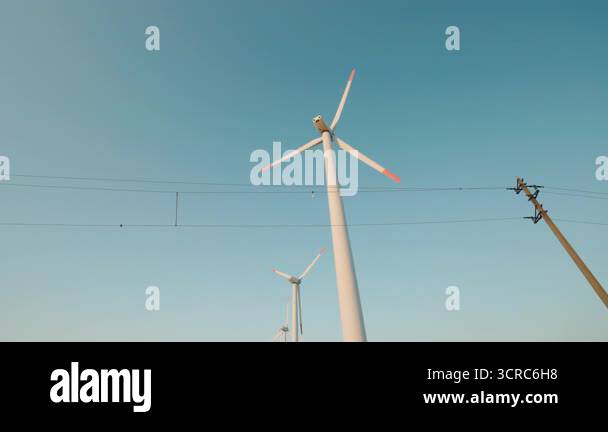 Wind turbines generating renewable energy with power lines and clear ...