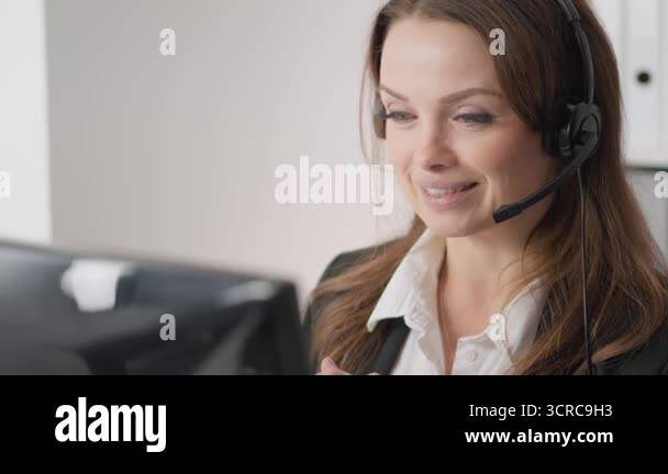 In a modern office, a skilled customer service agent uses a headset to ...