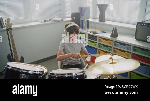 Primary School Boy Wearing Headphones Practicing Drums in Modern Music ...