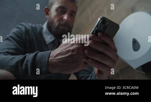 Businessman Using Smartphone, Sitting on the Toilet. Man Scrolling ...