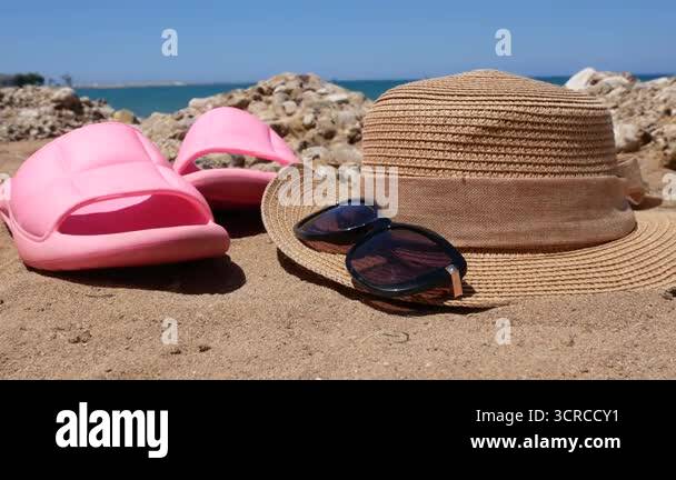 Sun hat, white slippers and sunglasses on a sandy beach with the blue ...