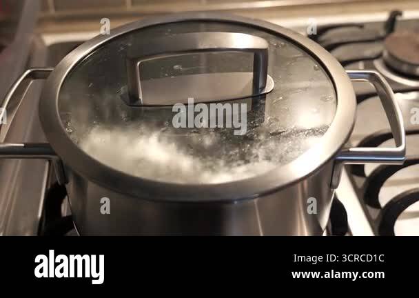 Water bubbles rapidly in a pot on the burner Stock Video Footage - Alamy
