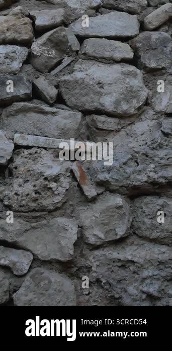 Ancient stone wall made of gray uneven stones of different sizes ...