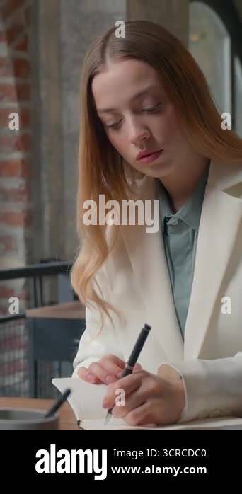 Caucasian business woman in office writing notes listening online video ...