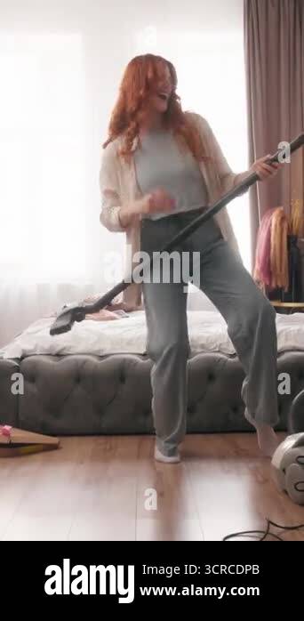Funny woman with vacuum cleaner pretend playing guitar Caucasian silly ...