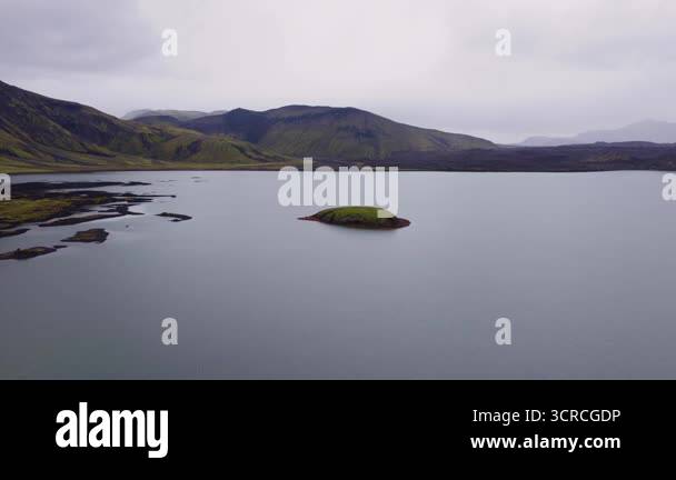 Serene aerial view of a grassy island in a calm lake, surrounded by ...
