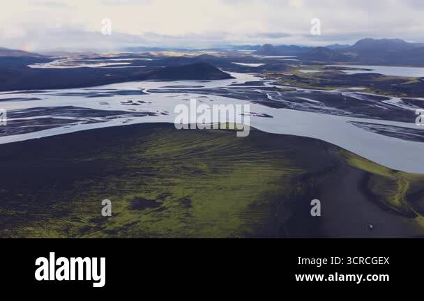 Aerial view of Iceland's volcanic landscape with green moss, winding ...