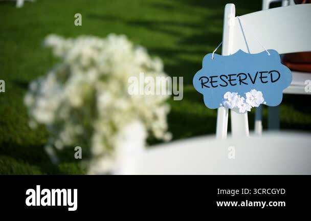 Close-up of a white Reserved sign decorated with a small bouquet of ...