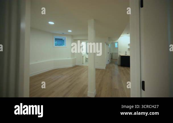 Renovated basement room with light wooden flooring, smooth white walls ...