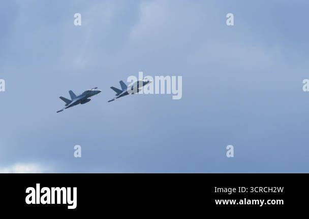 Slow motion view of formation of two F 18 fighter jets flying at bright ...