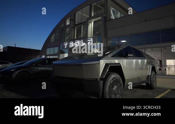 Exterior sign of Tesla dealership. Cybertruck and Tesla models are ...