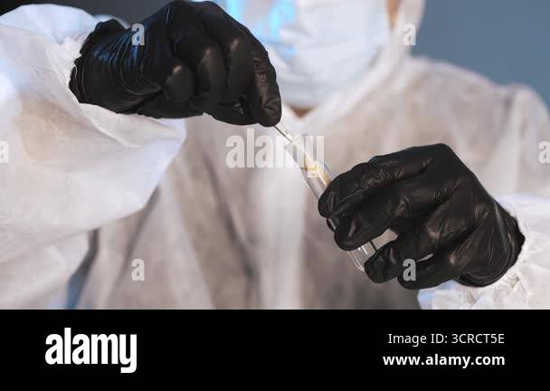 A forensic scientist wearing a protective suit and gloves removes a ...