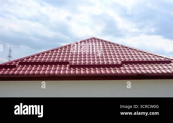 Red metal roof protecting a modern home. New durable tiles cover the ...