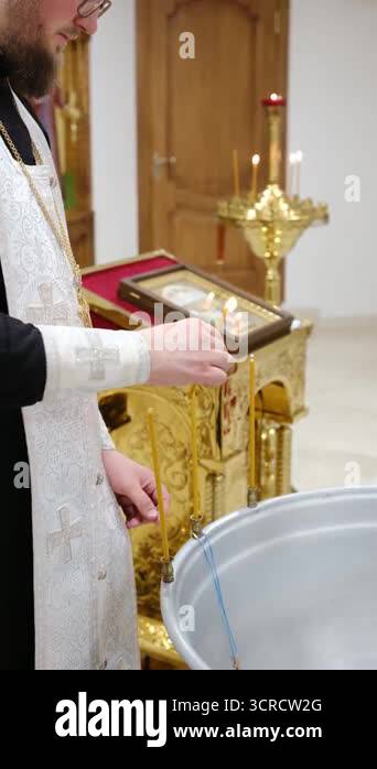 Priest holding candle lighting ritual objects near water basin inside ...