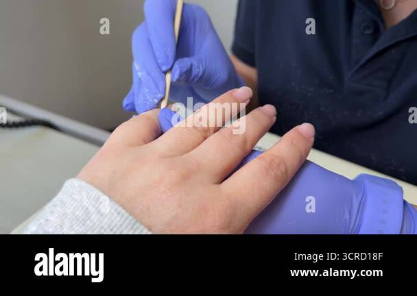 Nail technician using an electric file to shape and prepare a client ...