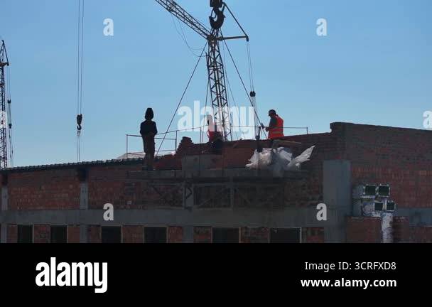 Construction workers on top floor with crane lifting materials ...