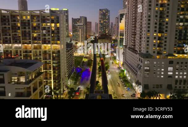 Public train system travels along elevated railroad in Miami downtown office district at night ...