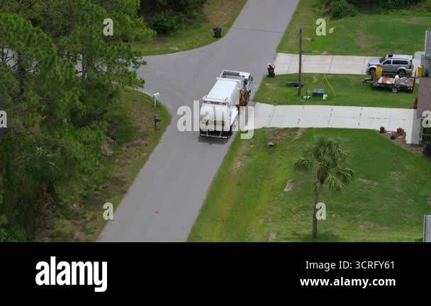 Trash truck picking up garbage bins on Florida city street curbside ...