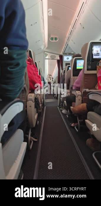 Passengers relax in their seats while cabin crew serves refreshments on ...
