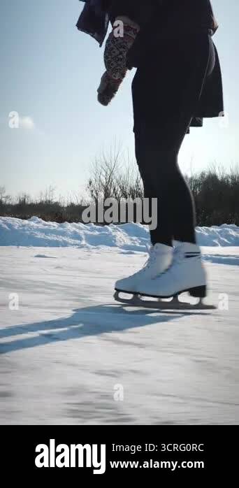 Ice skating on frozen lake. Girl in black skirt and white figure skates ...