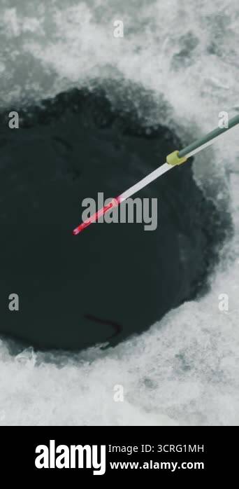 Close up of ice hole on frozen lake with fishing rod. Fisherman ...
