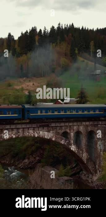 Passenger train passing over viaduct bridge in mountains. Electric ...