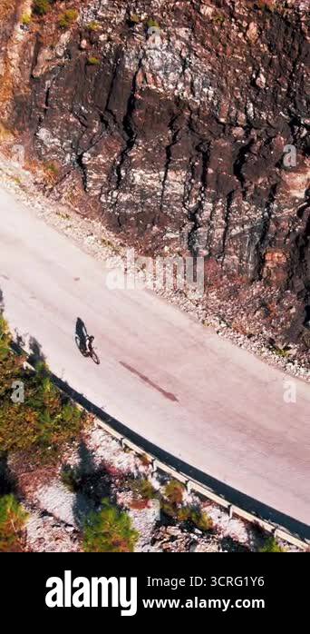 Professional female cyclist cycling on road bicycle along mountain road ...