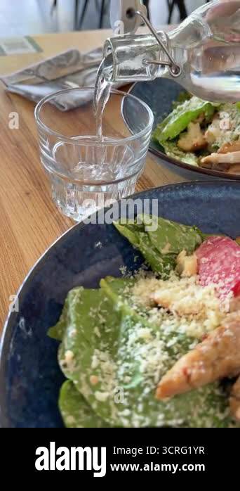 fresh clean water pouring into a glass on sunny wooden kitchen tabletop ...